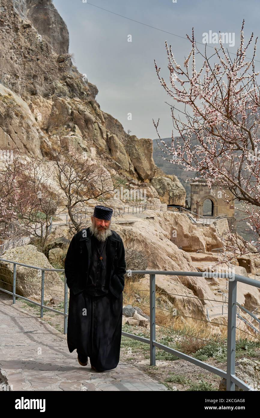 The Ruzin priest in a cassock walks through the cave city in the rock ...