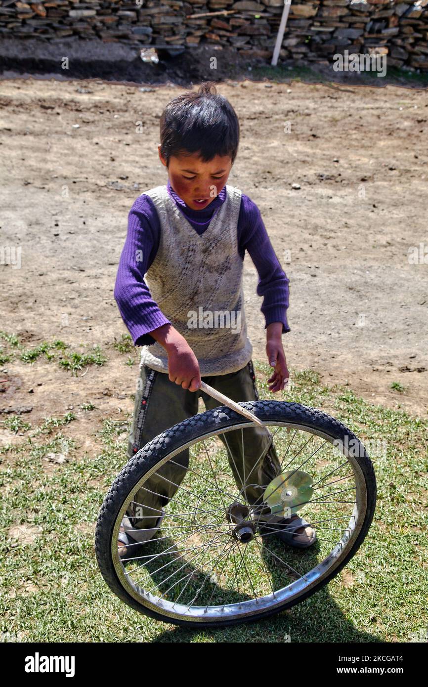 Ladakhi boy plays with a bicycle wheel in a small village in Rangdum ...