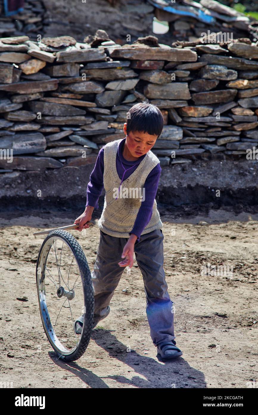 Ladakhi boy plays with a bicycle wheel in a small village in Rangdum ...