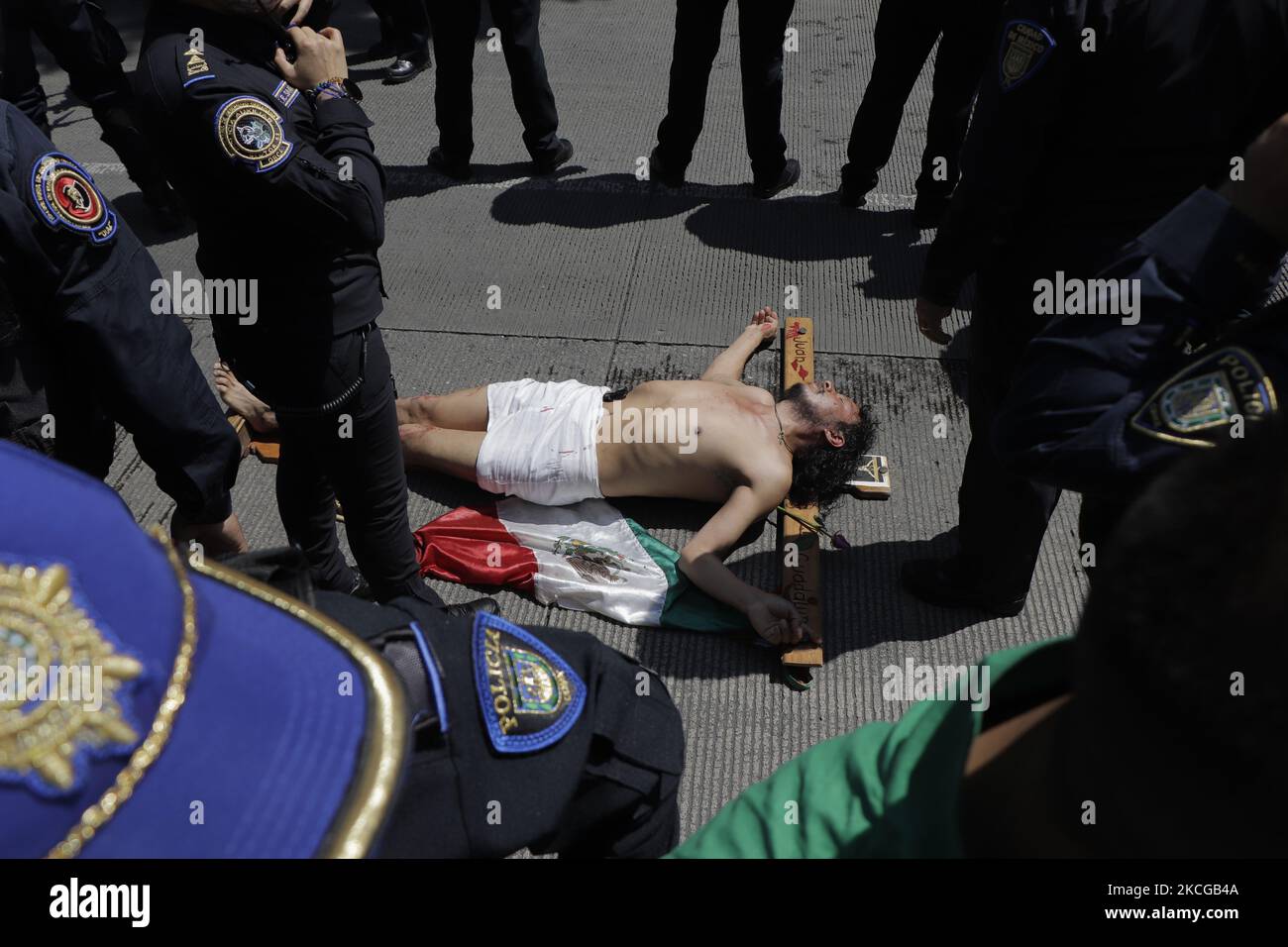 A person lying down, dressed as Jesus Christ, is encapsulated by police ...