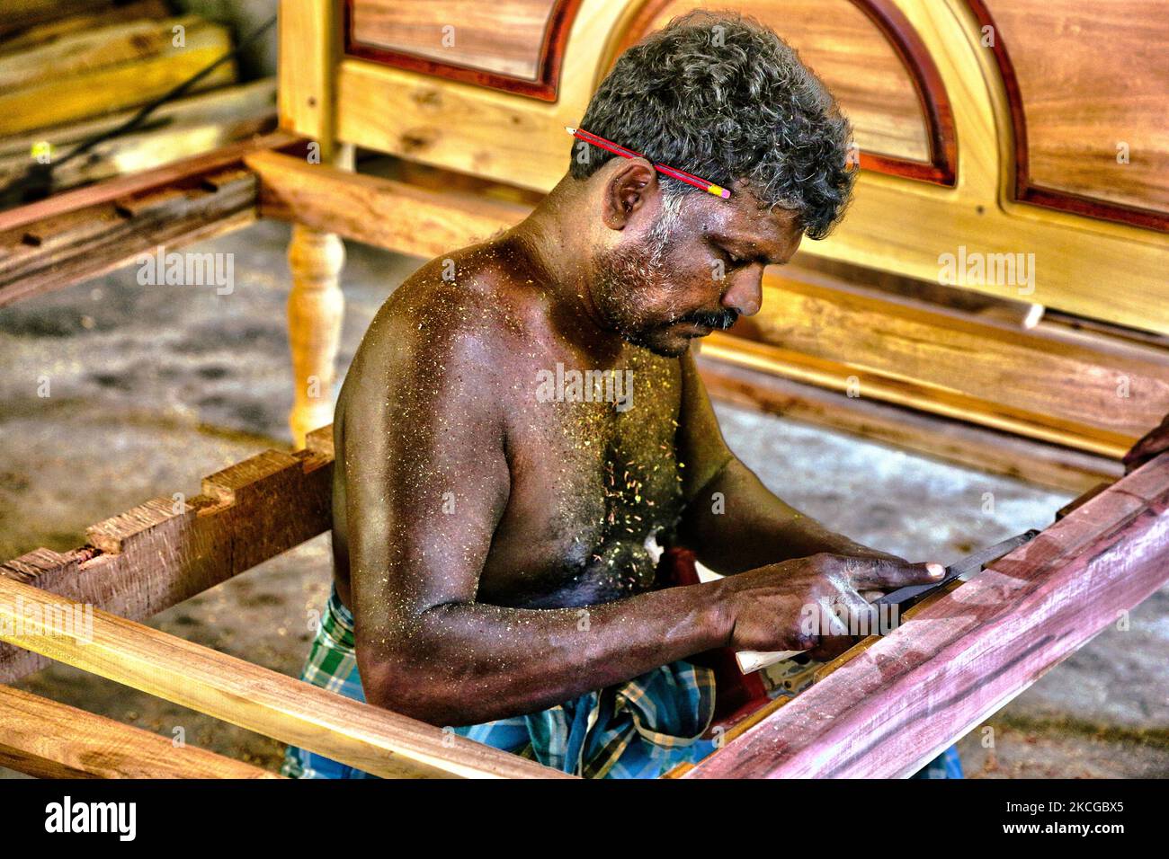 Carpenter constructs a fancy wooden bed frame at a small workshop in ...