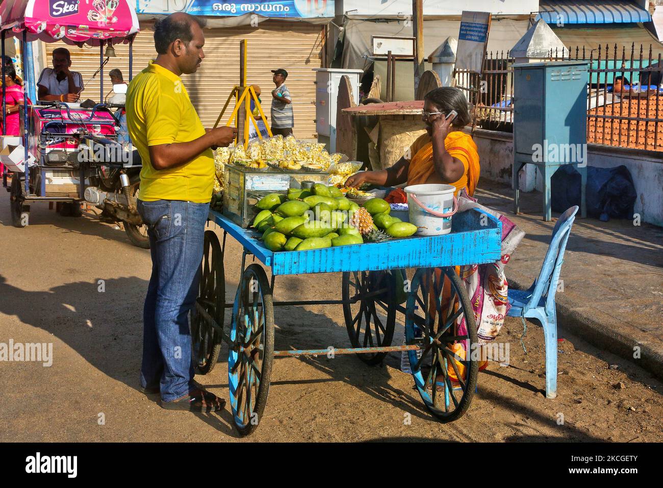 Food seller selling fruits and dried snacks on small carts along the roadside in Kanyakumari ...