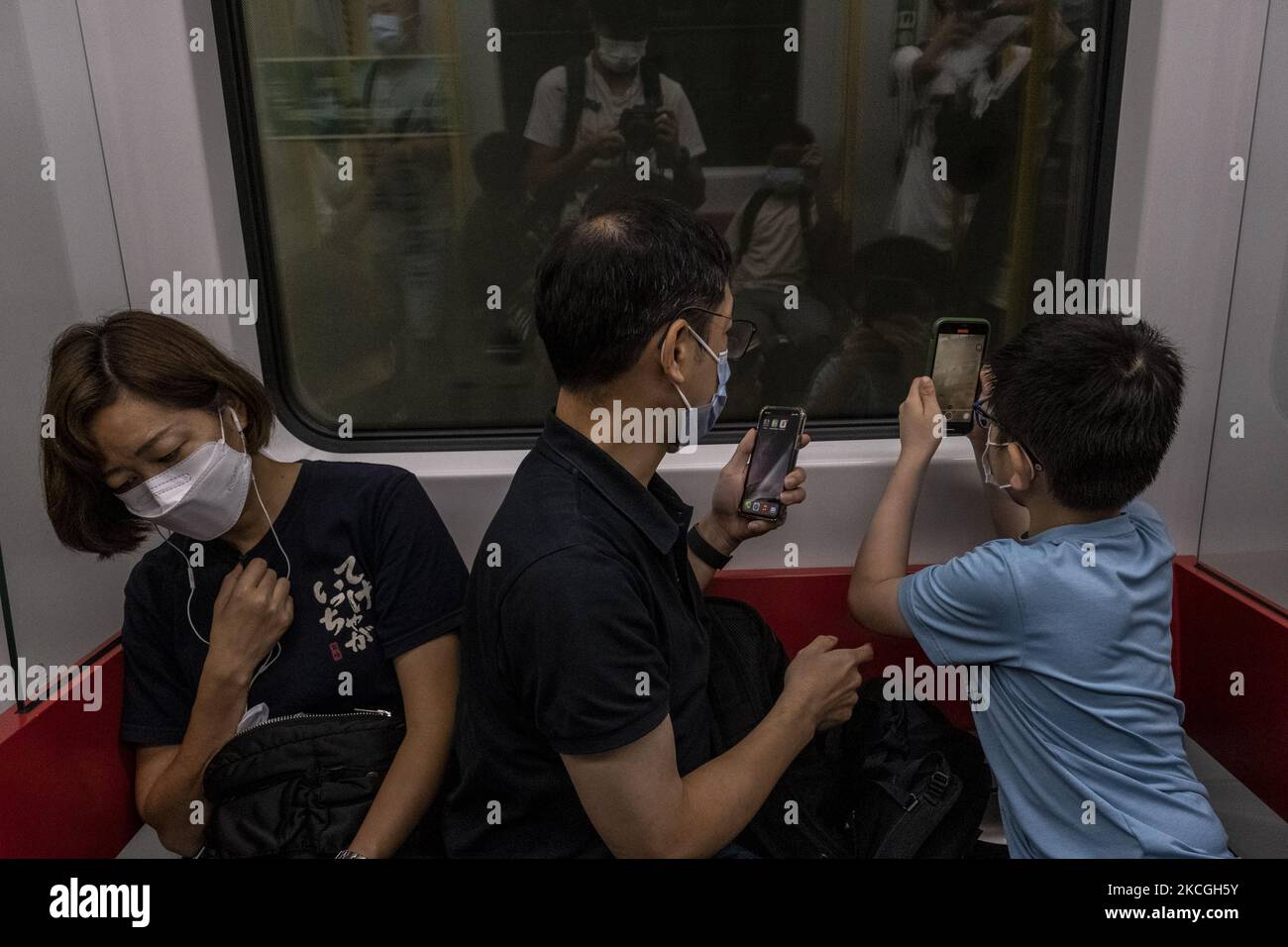 Passengers take photos while riding on the first train of the Tuen Ma ...