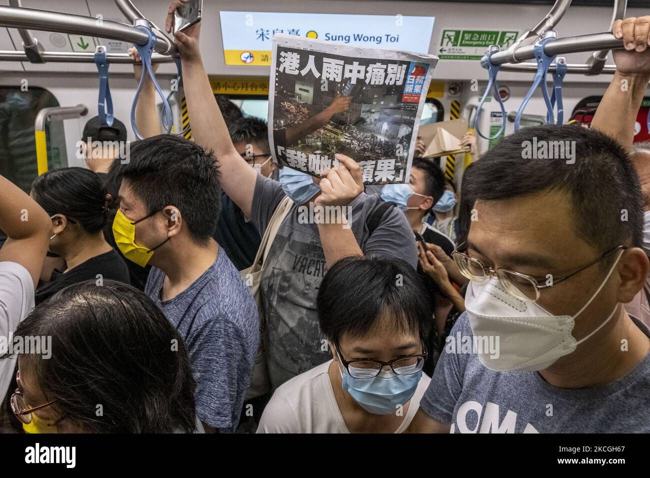 A Passengers holds up an apple daily newspaper while riding on the ...