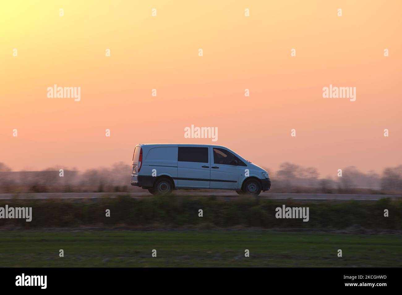 Passenger van driving fast on intercity road at sunset. Highway traffic ...
