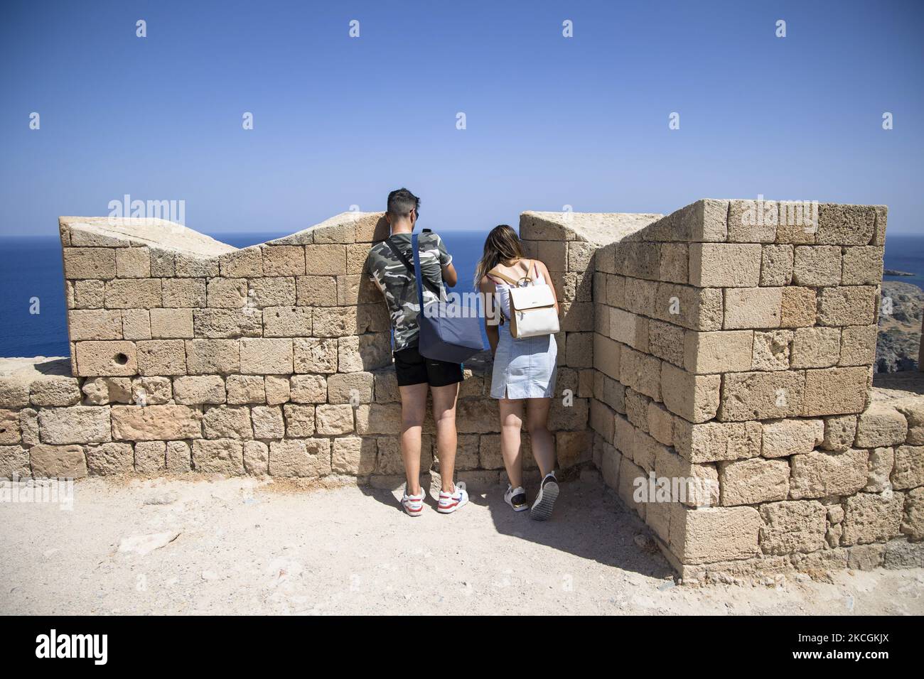 Visitors walk in the acropolis (upper city) in Lindos on the island of ...