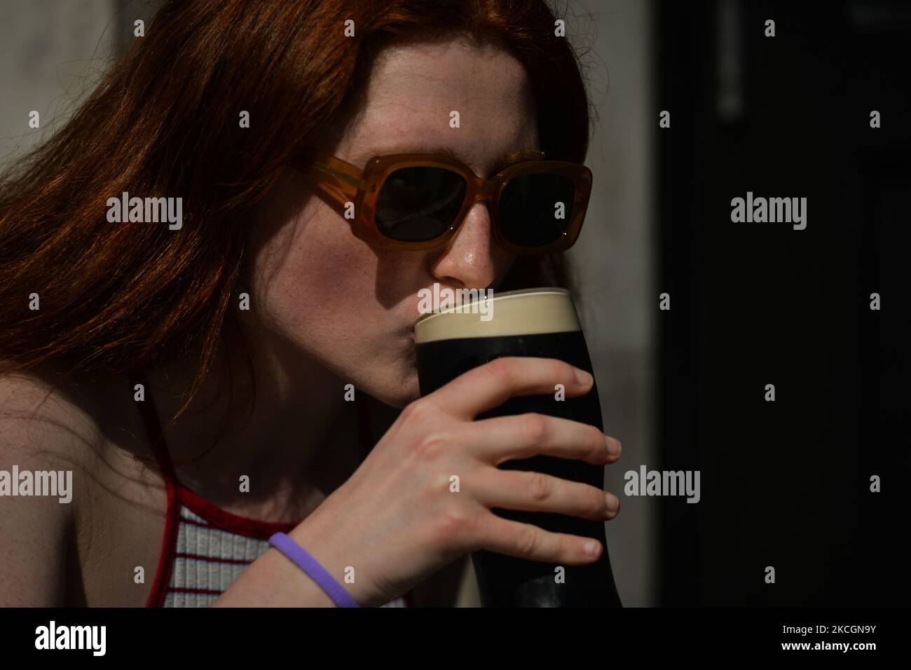 A young woman enjoys a pint of Guinness in a pub in Dublin city center ...
