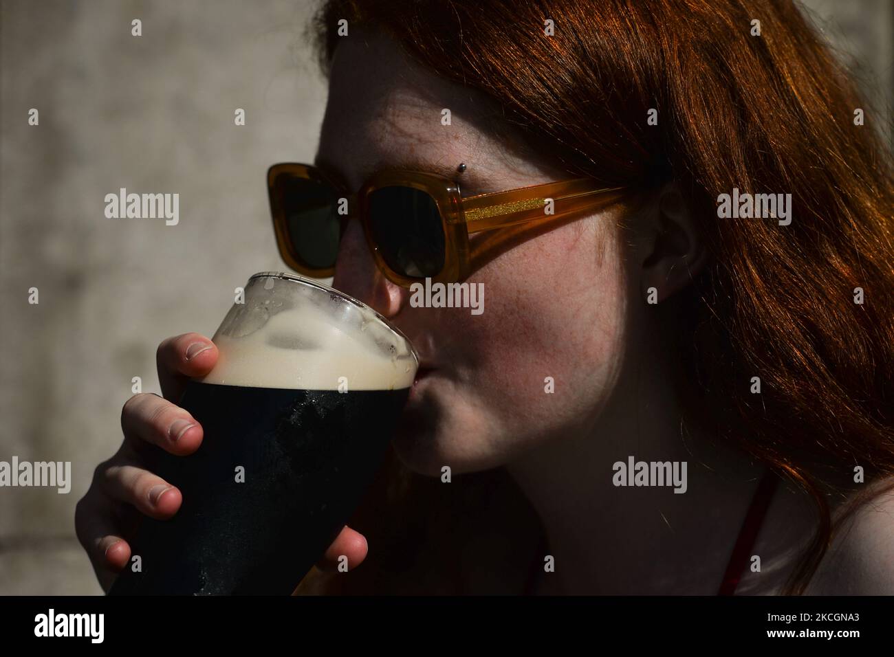 A young woman enjoys a pint of Guinness in a pub in Dublin city center ...