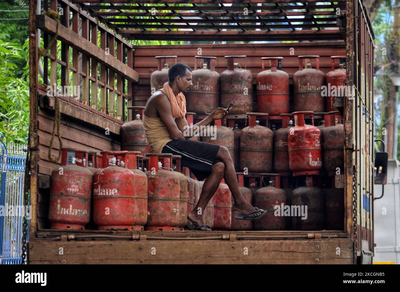 A worker browse mobile phone sitting on a cooking gas cylinder in a ...