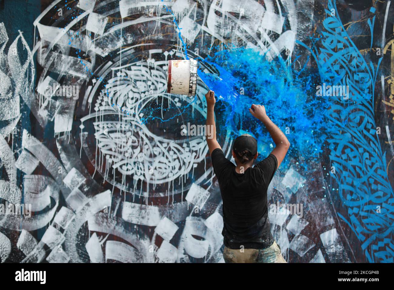 Palestinian artist Bilal Khaled draws on a wall ordinate in Gaza city ...