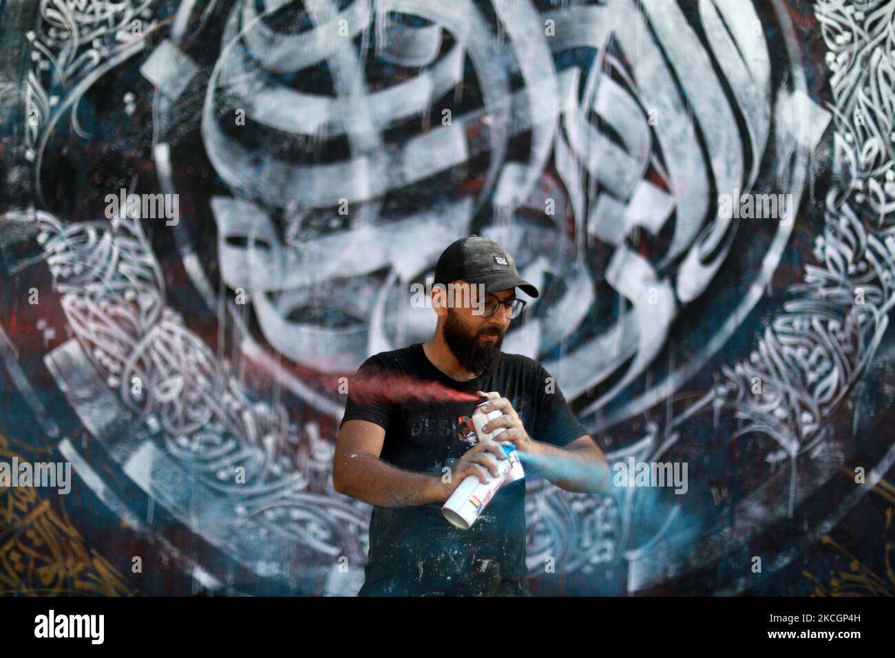 Palestinian artist Bilal Khaled draws on a wall ordinate in Gaza city ...