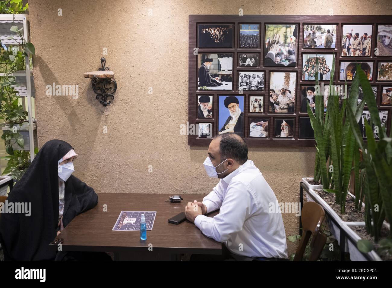 An Iranian couple wearing protective face masks talk to each other ...