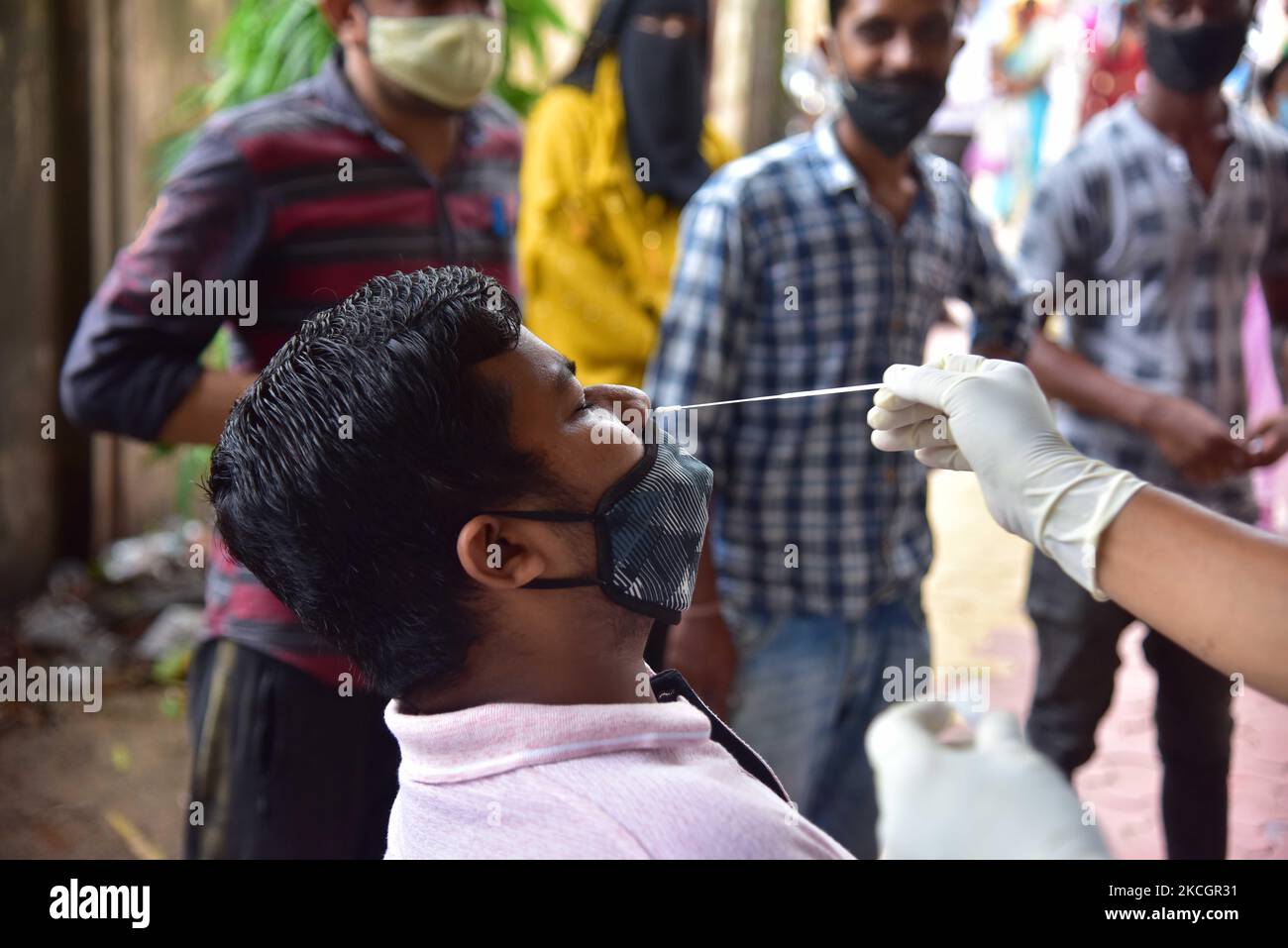 A health worker takes a nasal swab sample of a man to test with Rapid ...