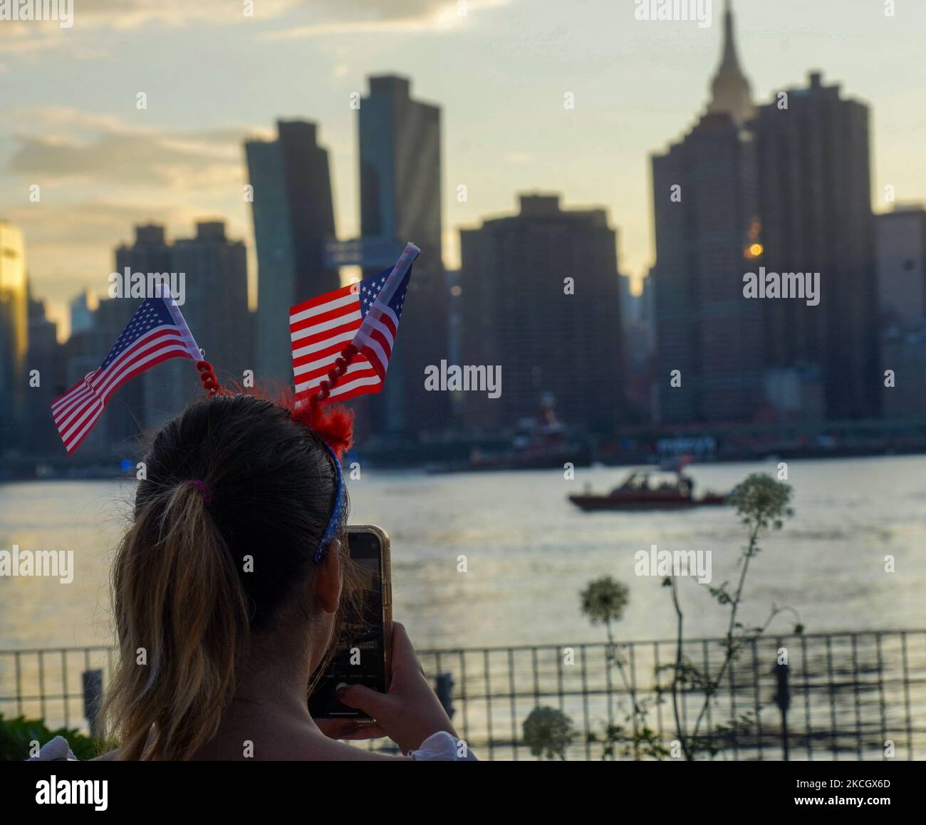 A young girl takes pictures with her cell phone on the East River at ...