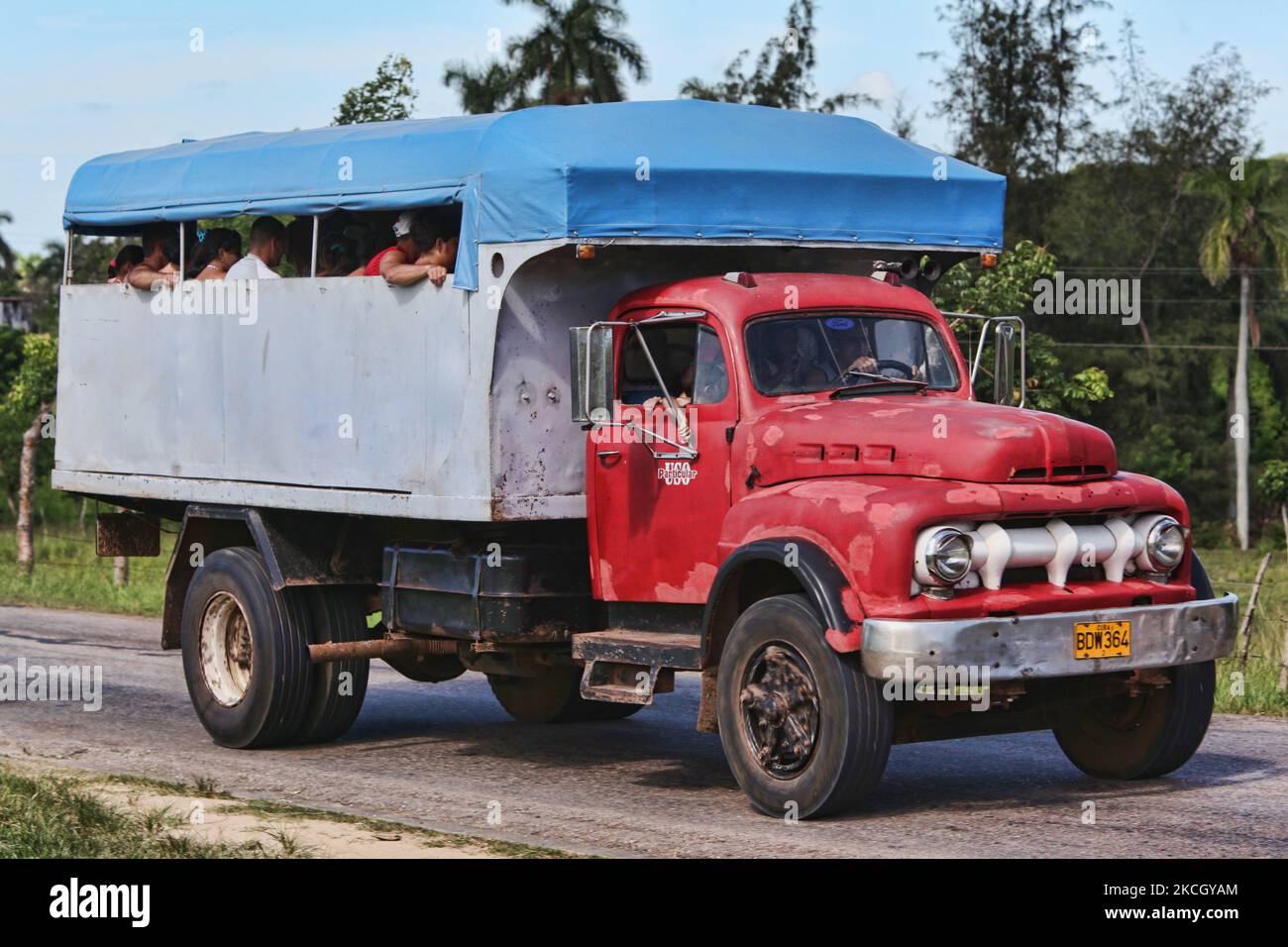 Truck filled with passengers travels along a small road just outside ...