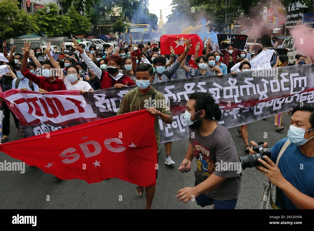 Demonstrators make the three finger salute and hold banners during a ...