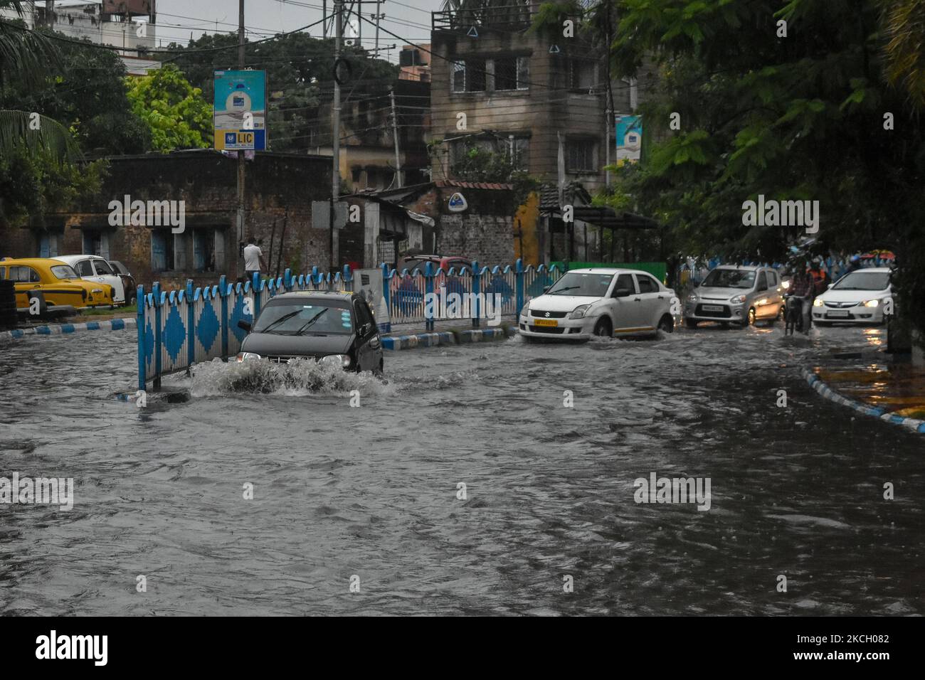 Cars tries to make their way through a heavily flooded street , after ...