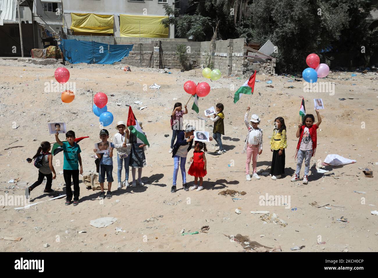 Palestinian children hold helium balloons as they take part in a rally ...
