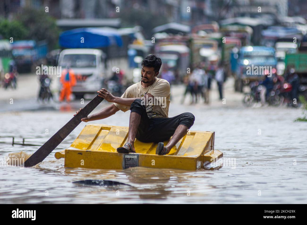 A man rides a makeshift raft in the middle of an inundated road section ...
