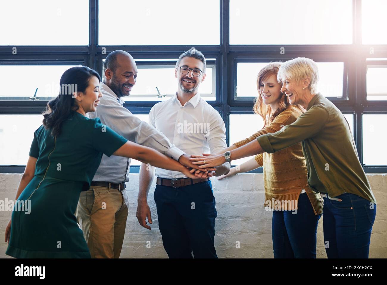 If anybody can do it, we can. a group of colleagues joining their hands ...