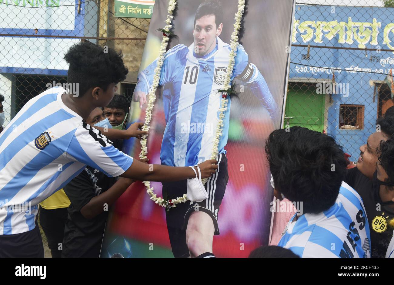 An Argentine fan puts a flower garland over a photo of Lionel Messi (a ...