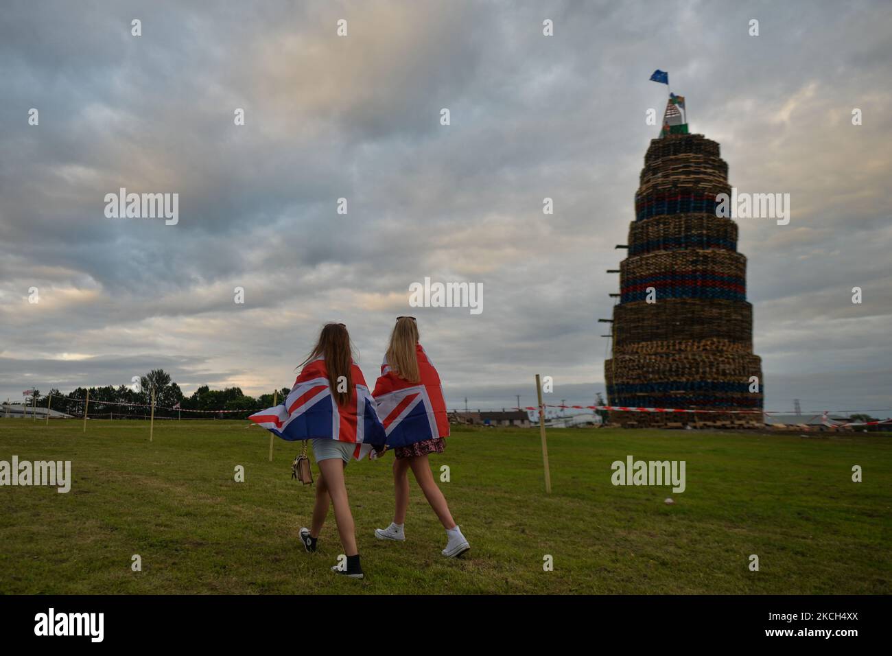 Two young women with the Union Jack walk in front of the bonfire in ...