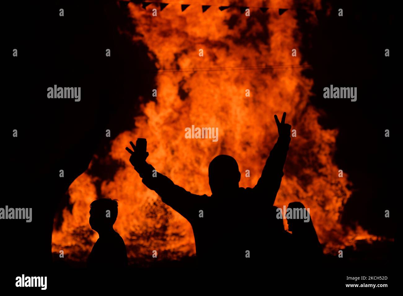 People pose for photos in front of a large bonfire during the Eleventh ...