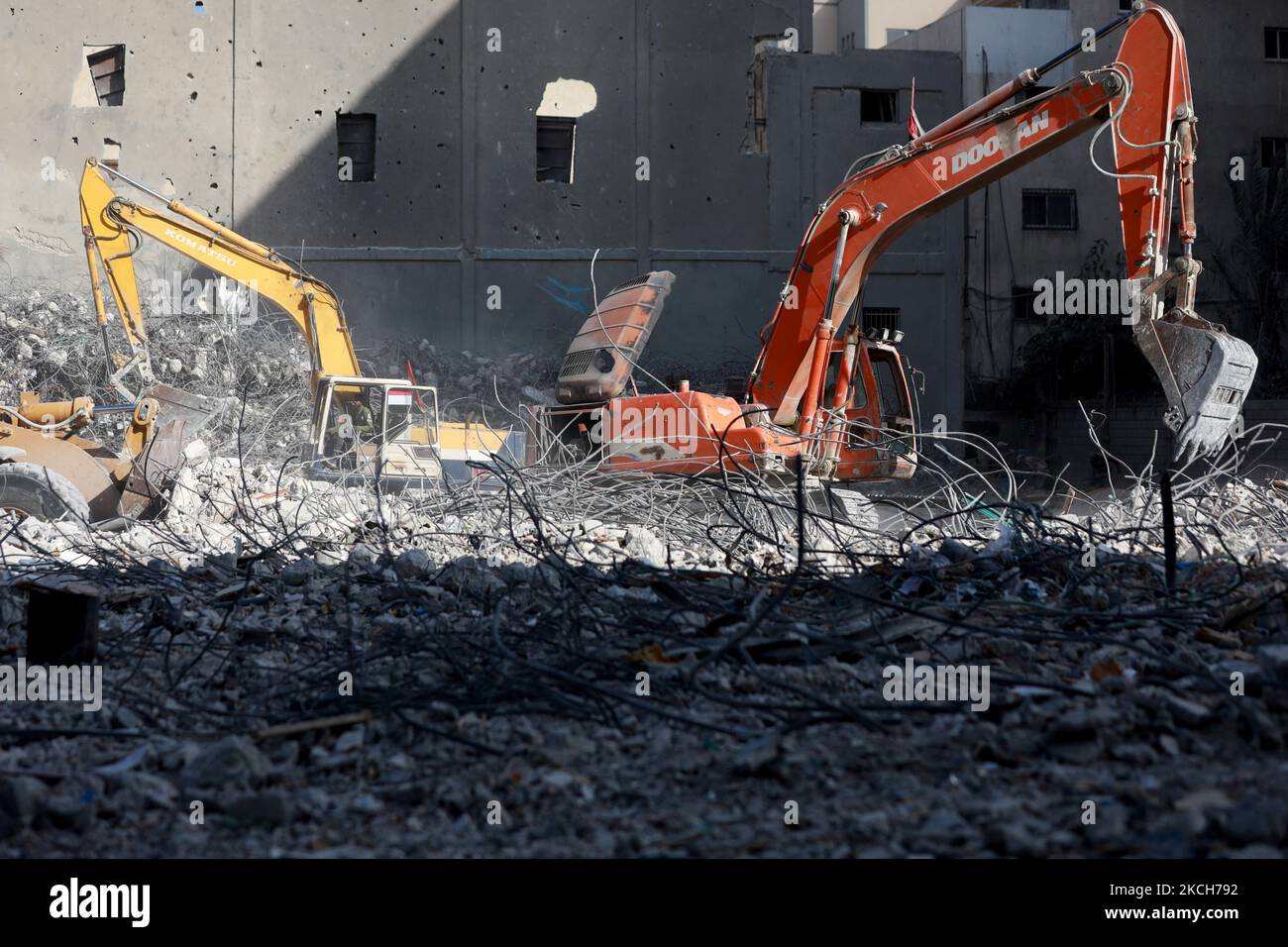 Palestinian workers collect the rubble of Al-Jalaa tower, levelled by ...