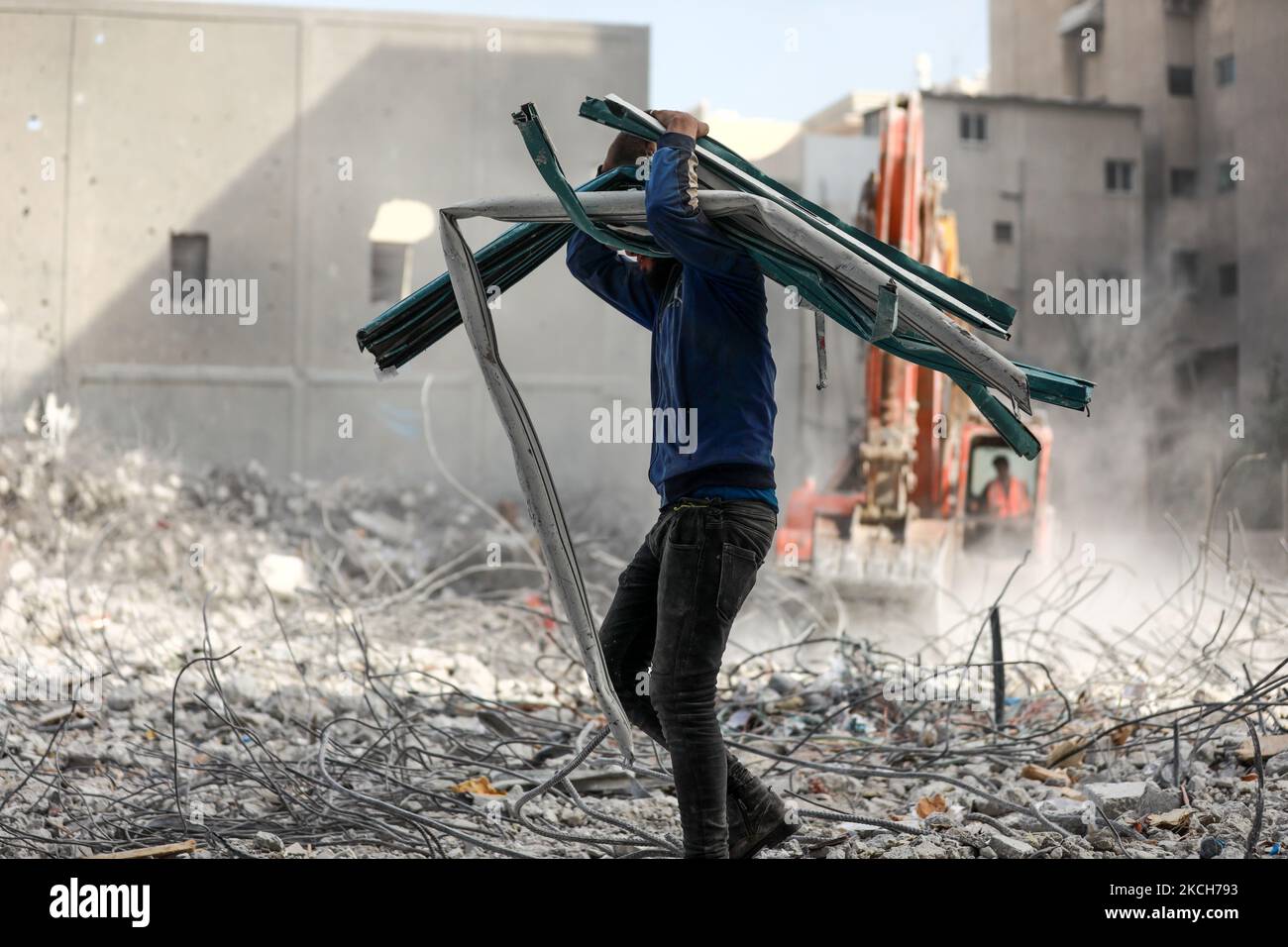 Palestinian workers collect the rubble of Al-Jalaa tower, levelled by ...
