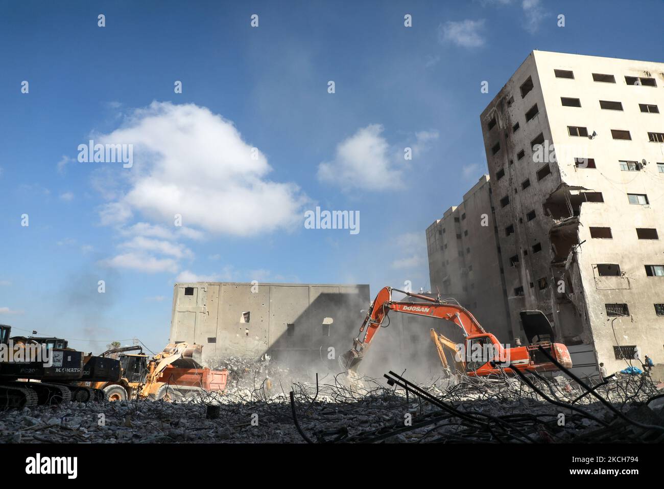 Palestinian workers collect the rubble of Al-Jalaa tower, levelled by ...