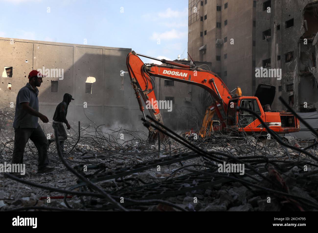 Palestinian workers collect the rubble of Al-Jalaa tower, levelled by ...