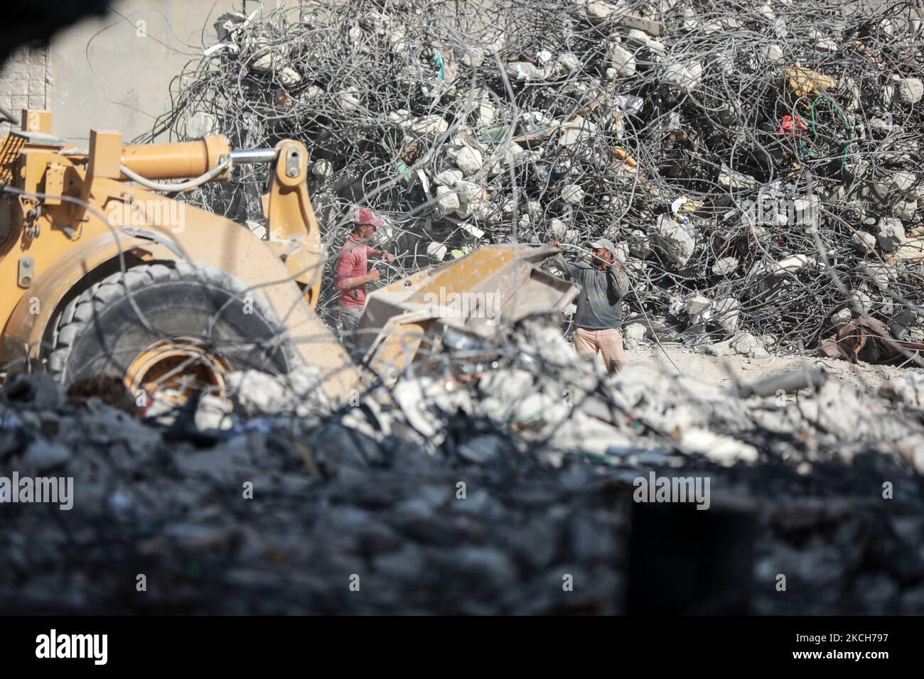 Palestinian workers collect the rubble of Al-Jalaa tower, levelled by ...