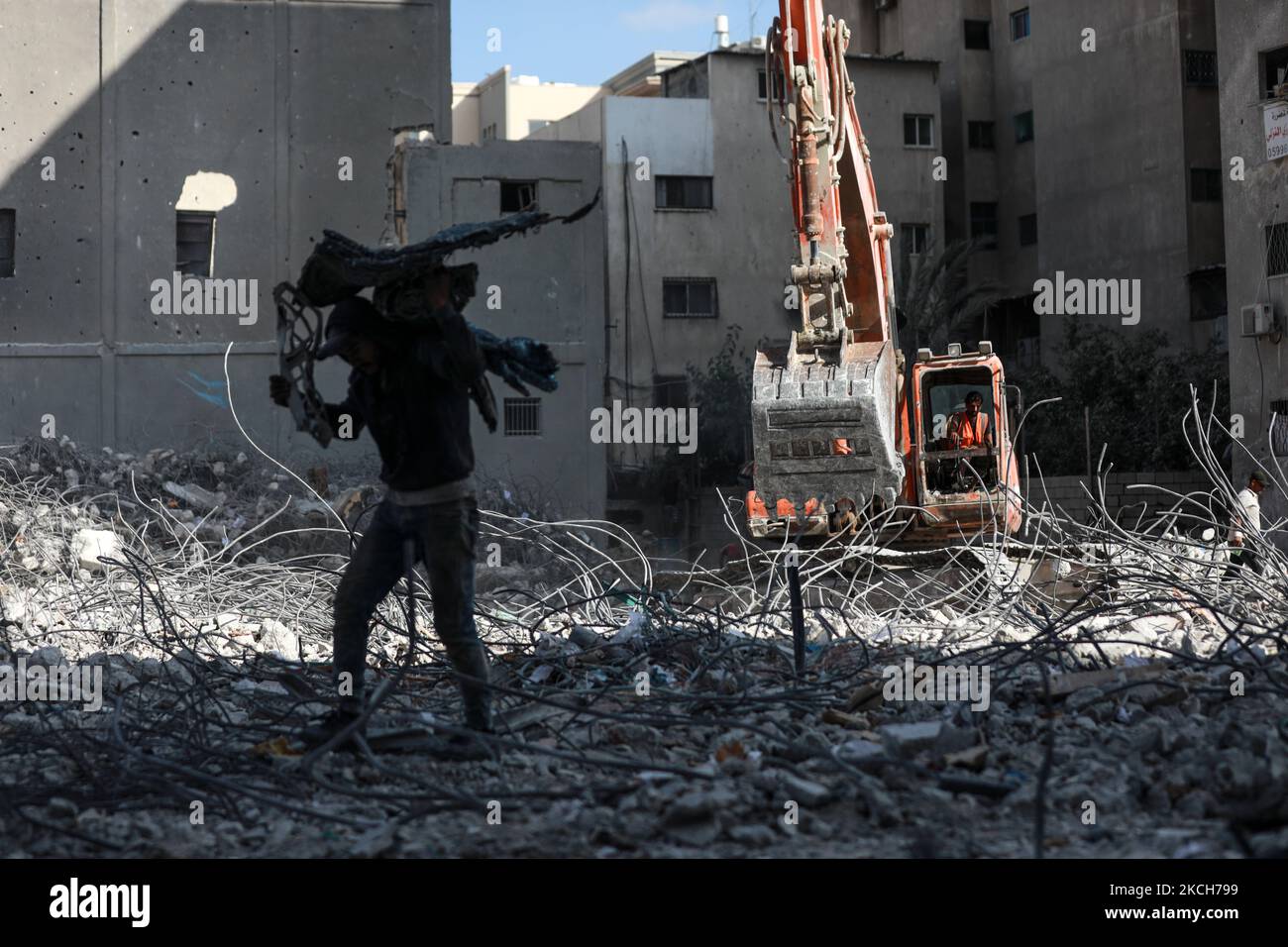 Palestinian workers collect the rubble of Al-Jalaa tower, levelled by ...