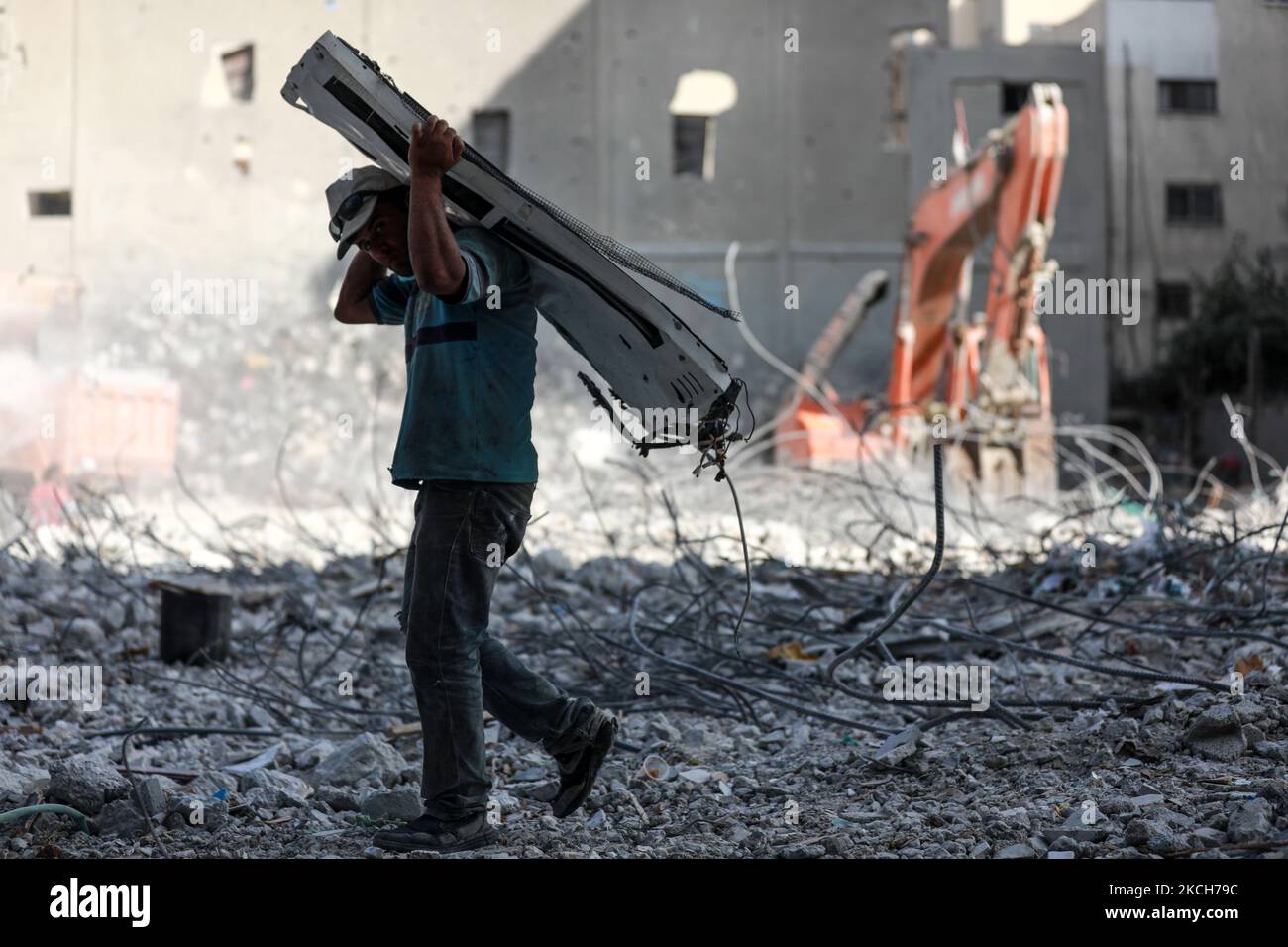Palestinian workers collect the rubble of Al-Jalaa tower, levelled by ...