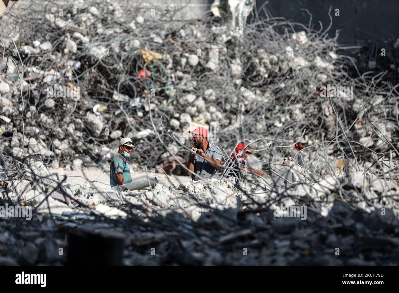 Palestinian workers collect the rubble of Al-Jalaa tower, levelled by ...