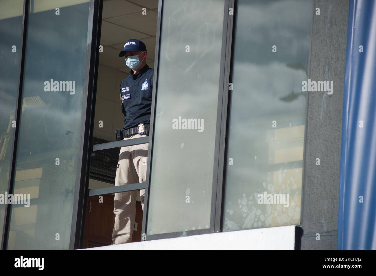 A Interpol Police Offiecer stands in a window of their head office ...