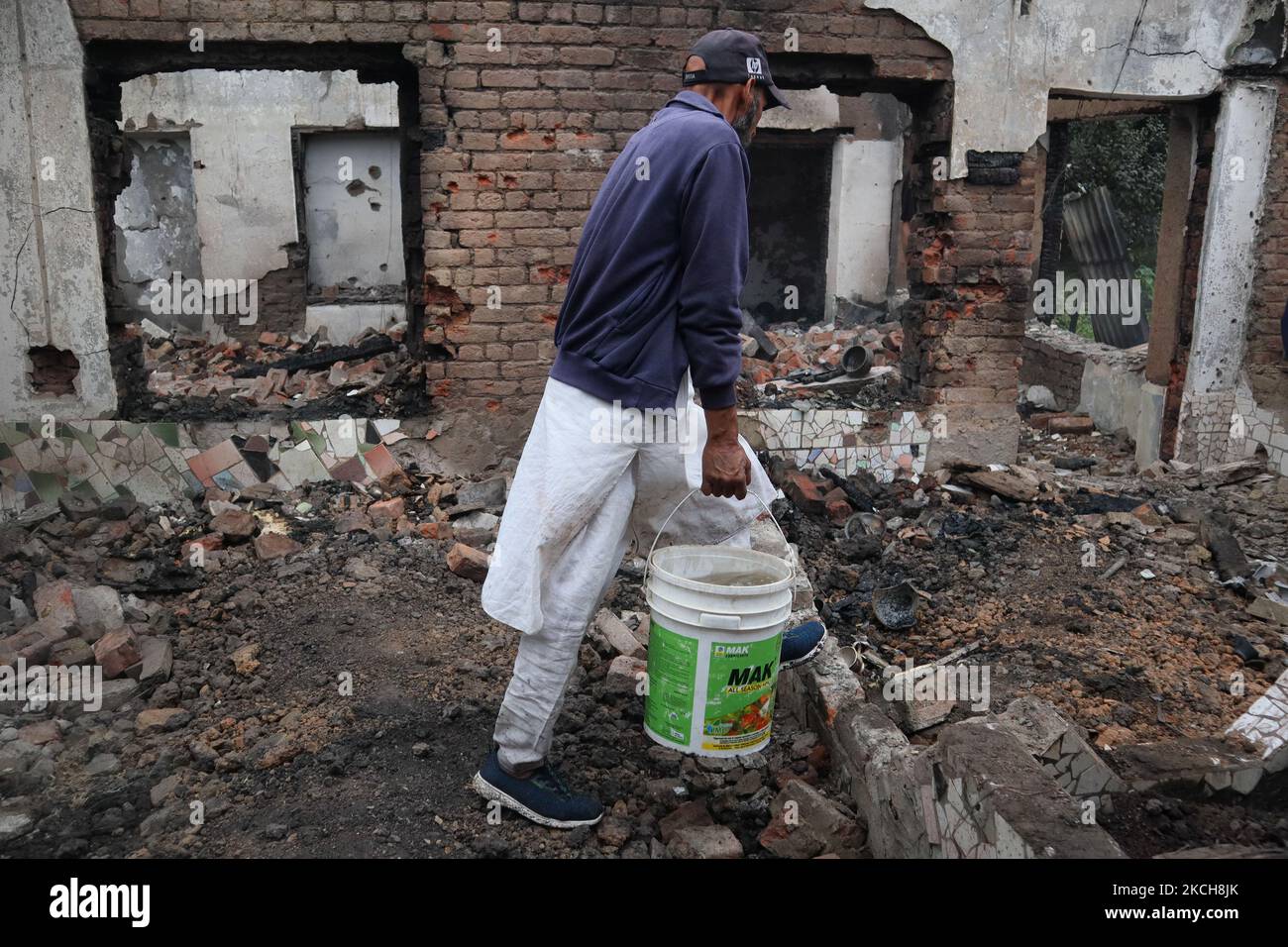 A Kashmiri resident carry the water bucket to douse fire inside a ...