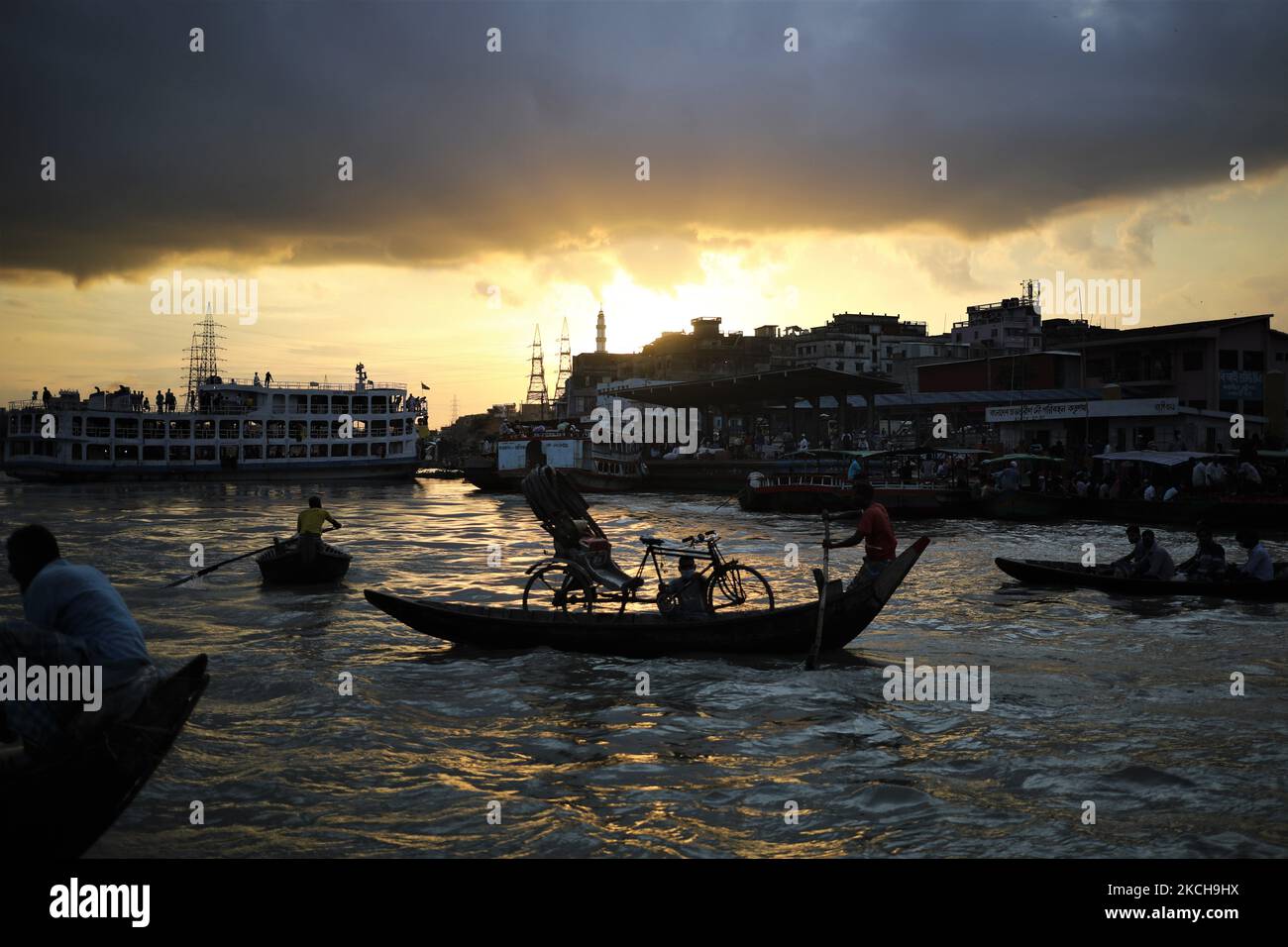 A rickshaw puller holds his rickshaw as he crosses the river Buriganga ...