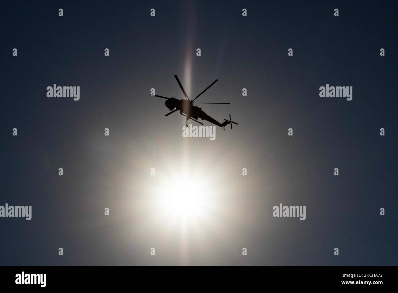 Silhouette of a fire fighting helicopter passing infront of the sun. A ...