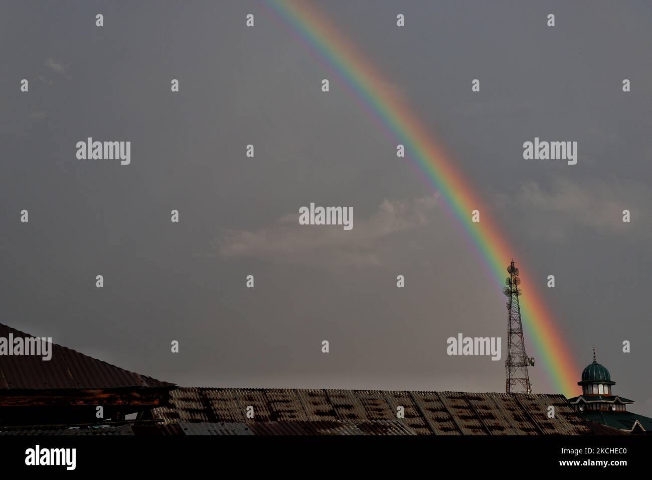 A rainbow appears after light rainfall over a mosque in Sopore town of ...