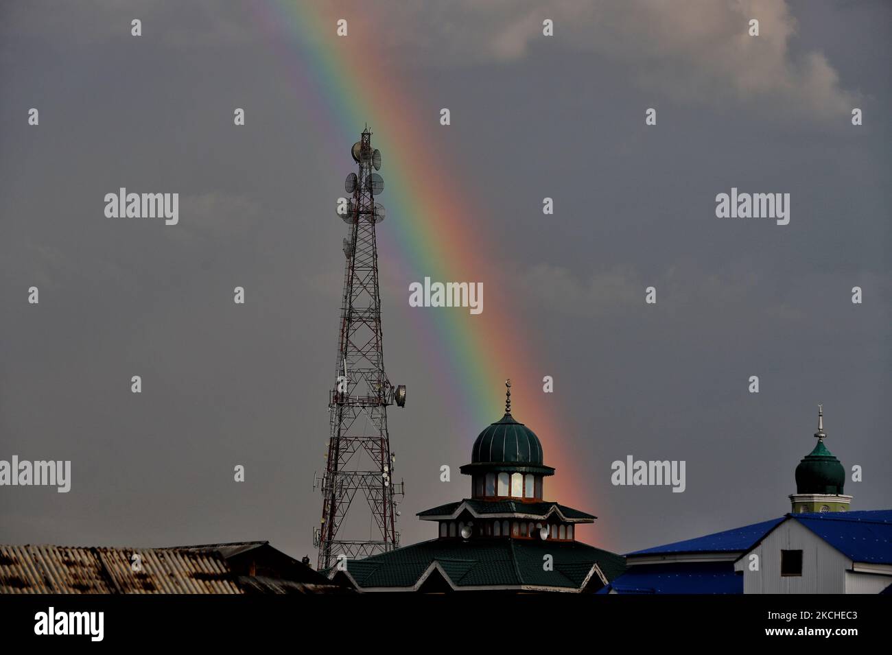 A rainbow appears after light rainfall over a mosque in Sopore town of ...