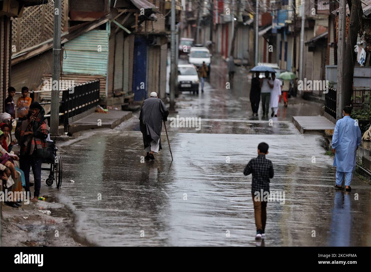 People walk during Eid-Ul-Adha amid rainfall in Sopore, District ...