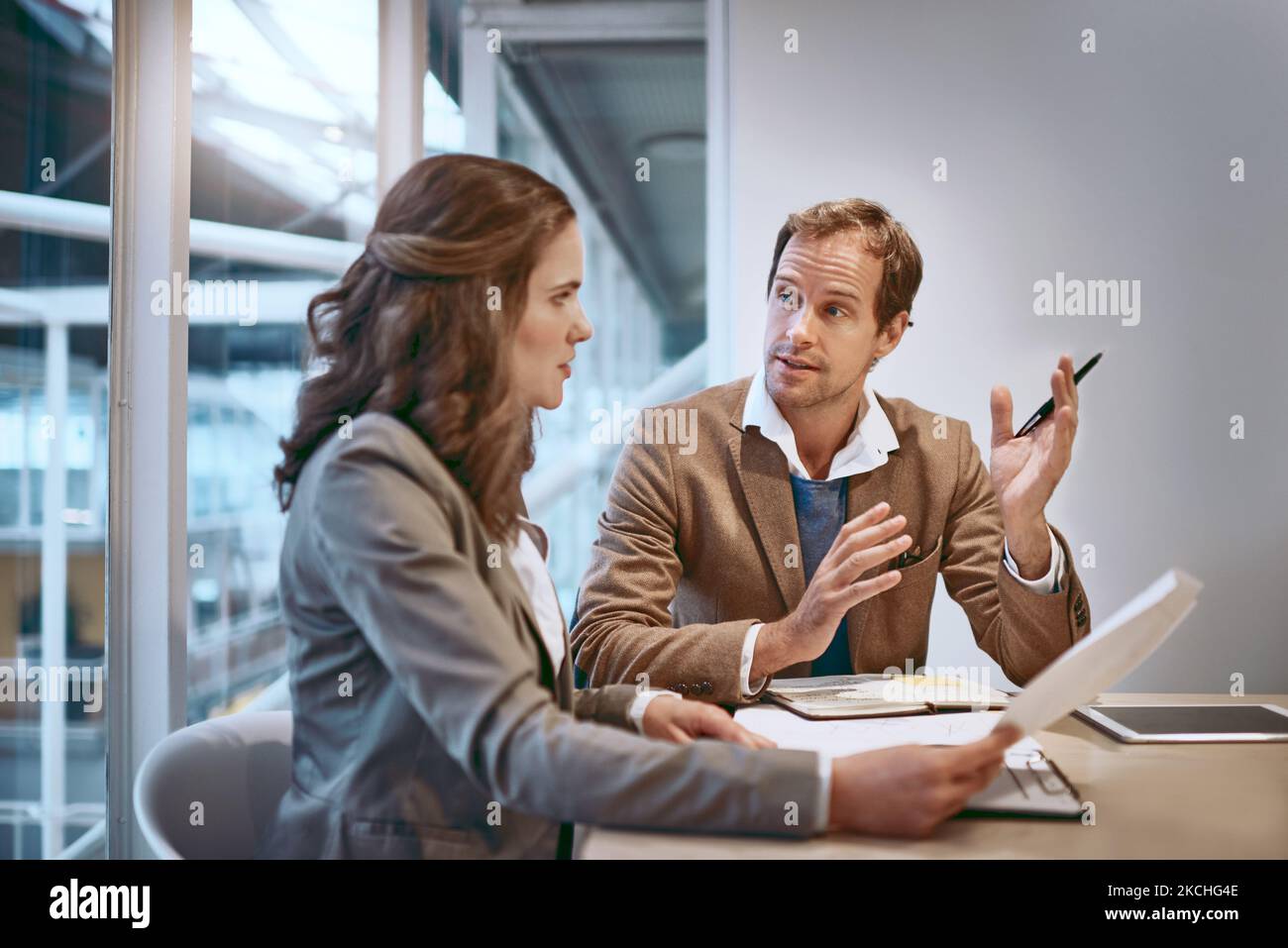 Communication is the key to synergy. two businesspeople working ...