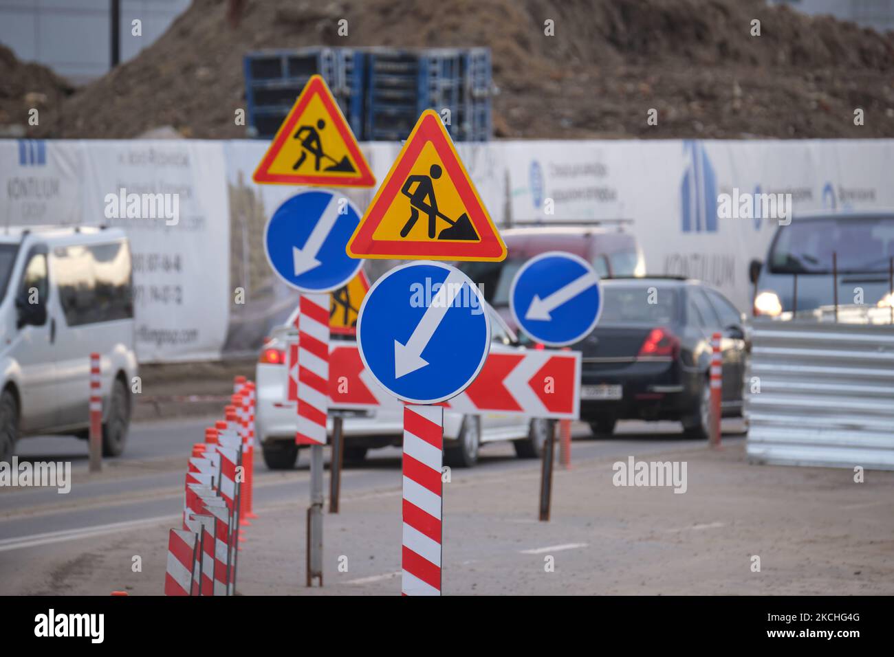 Roadworks warning traffic signs of construction work on city street and slowly moving cars Stock ...