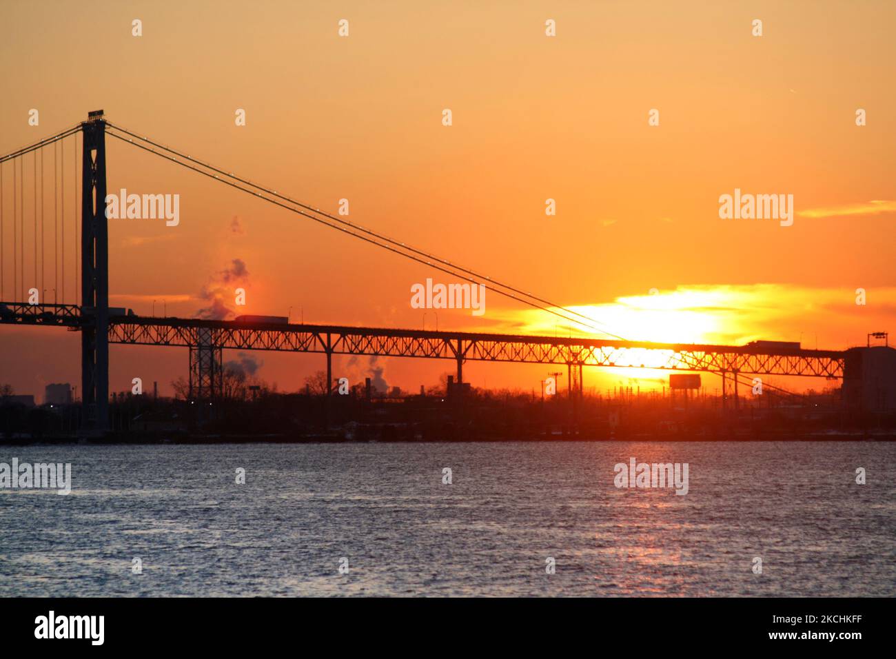 The sun sets behind the Ambassador Bridge over the Detroit River ...