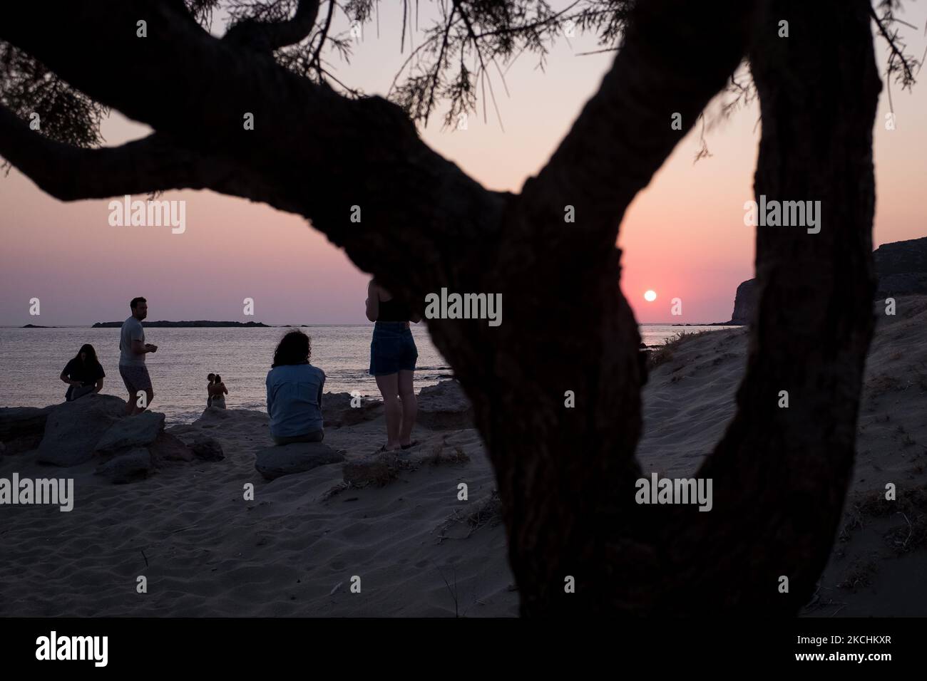 Locals and tourists are watching the sunset in Falassarna beach near ...