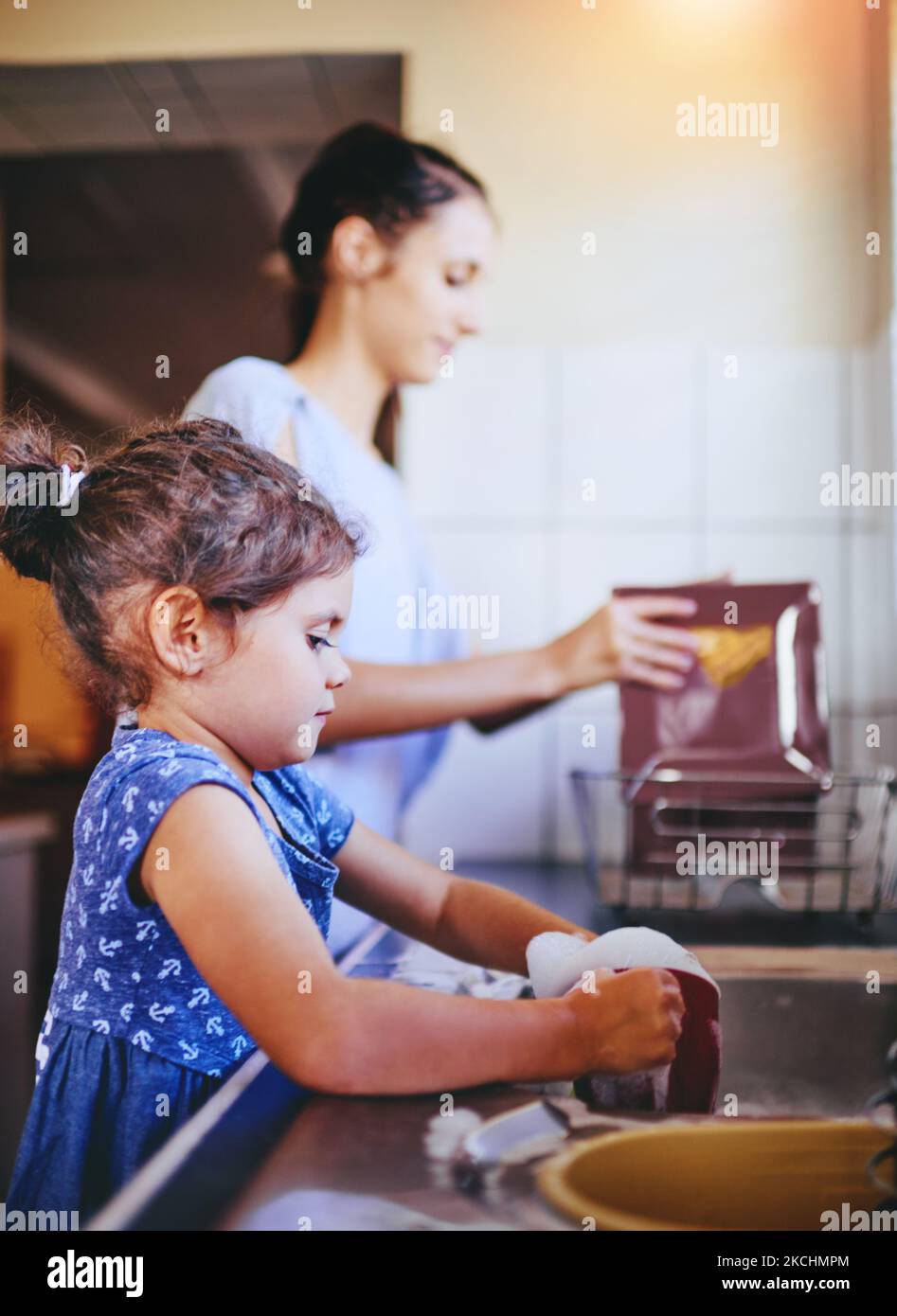 Mommys little helper. a happy little girl and her mother washing the ...