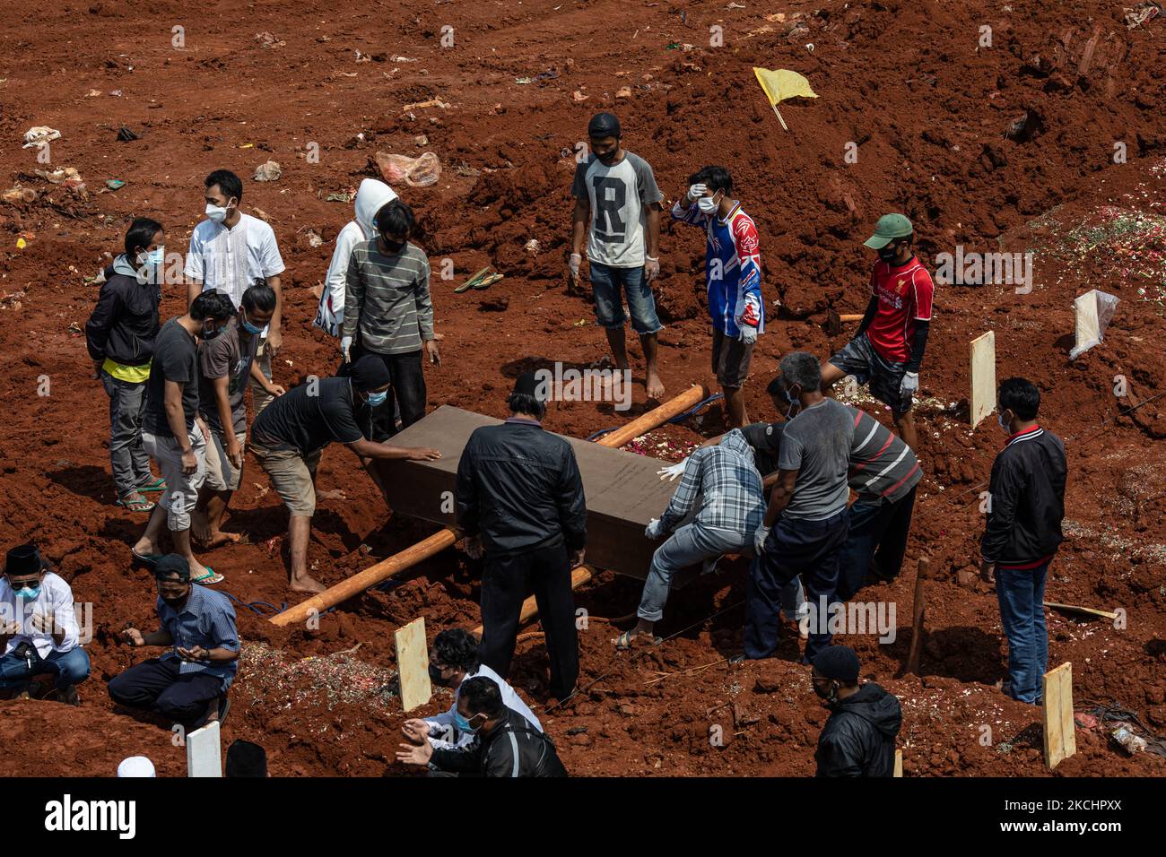 A family watch the funeral procession for Covid-19 victims, in Banten ...