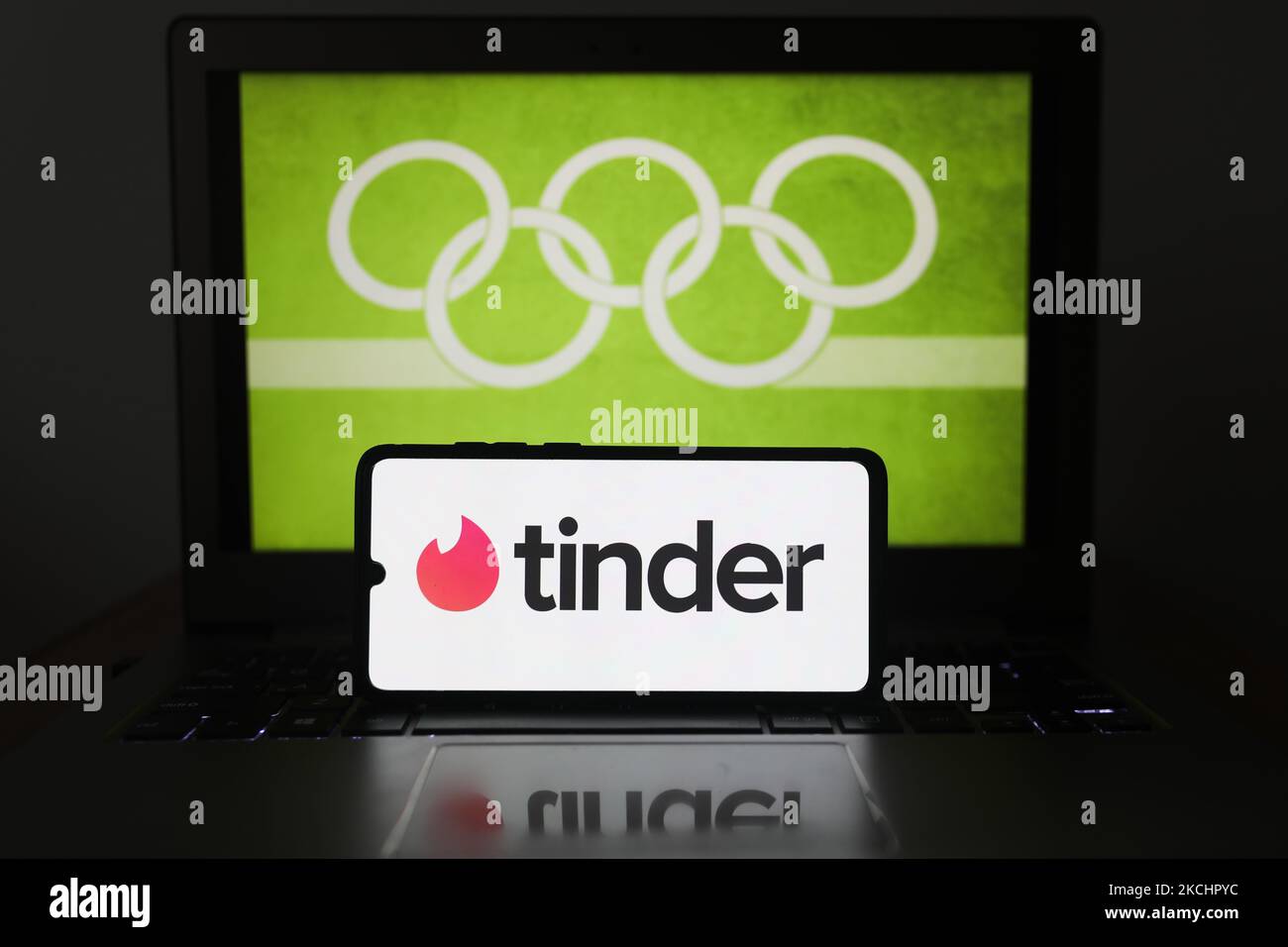 Tinder logo is displayed on a mobile phone screen photographed with ...
