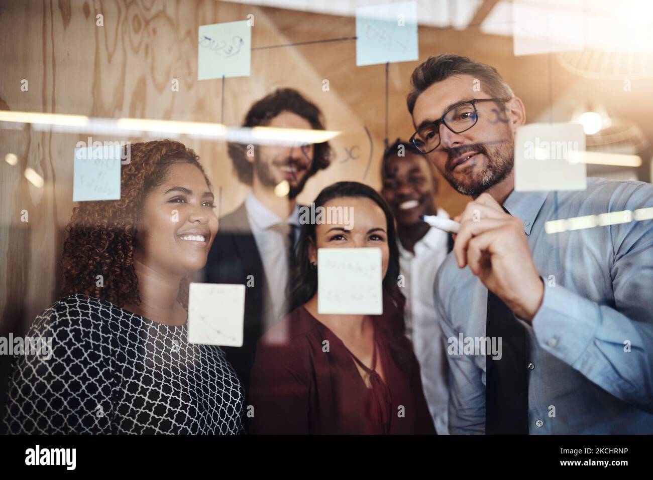 Putting new ideas up on the wall. a group of businesspeople ...